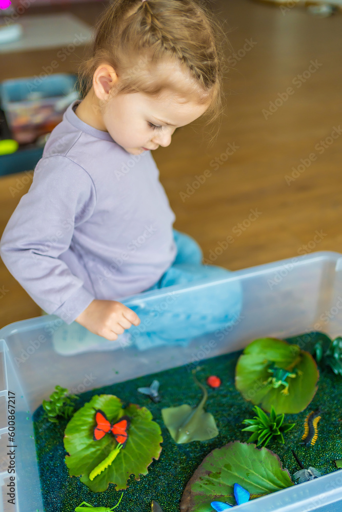 Little girl playing in handmade swamp of green-dyed chia seeds with ...