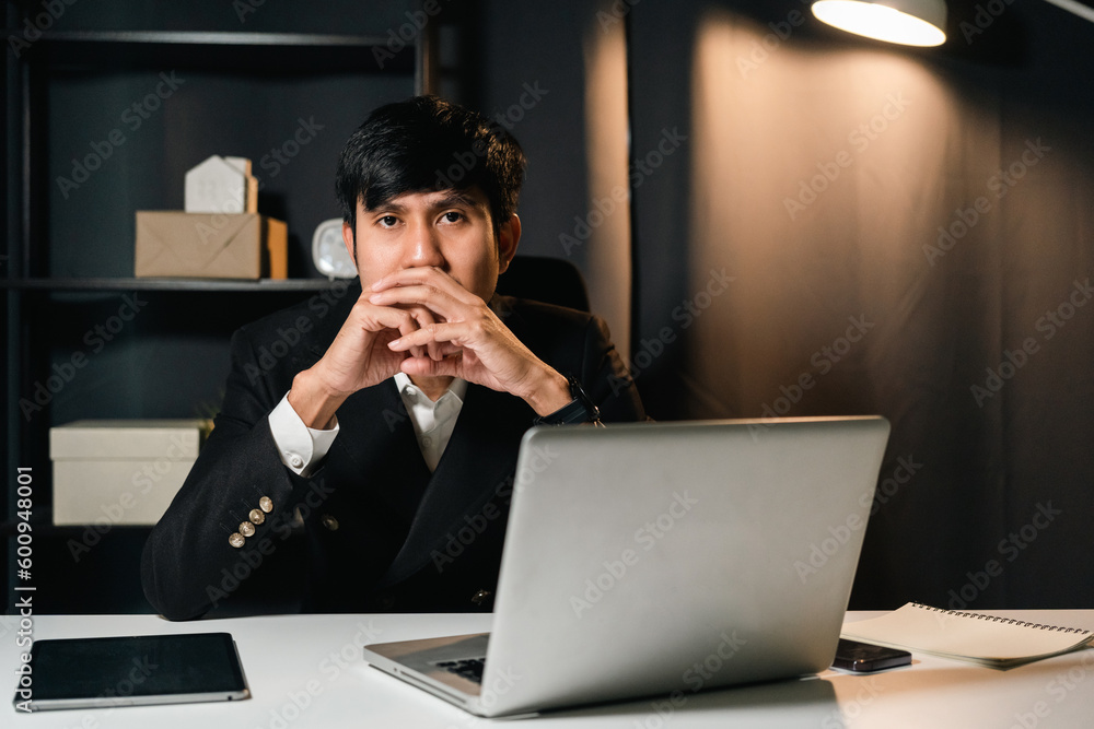 Young asian businessman working with laptop computer in the dark office ...