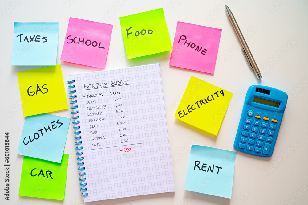 Notepad, with monthly expenses, and next to it a calculator and colored ...