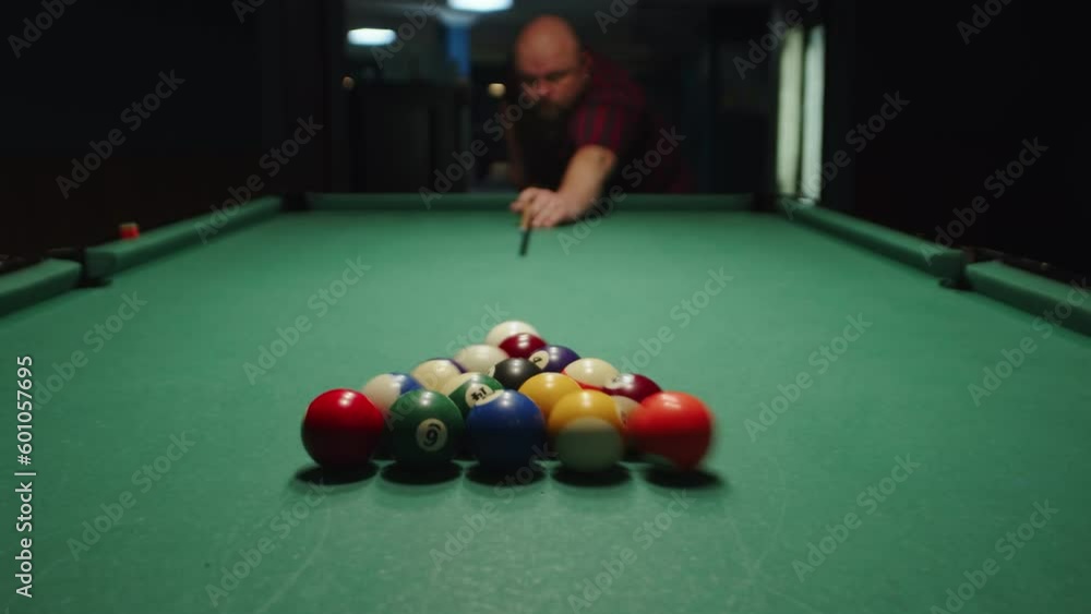 Bald bearded man breaks the pyramid of balls by hitting the white cue ...