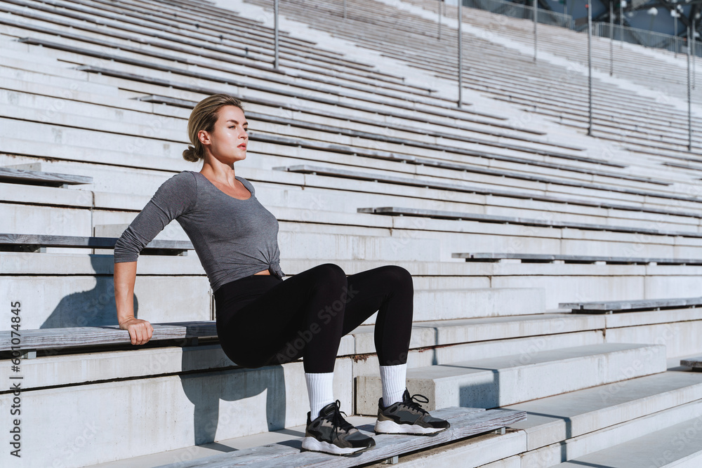 Woman athlete wearing female sportswear doing triceps dips exercise ...