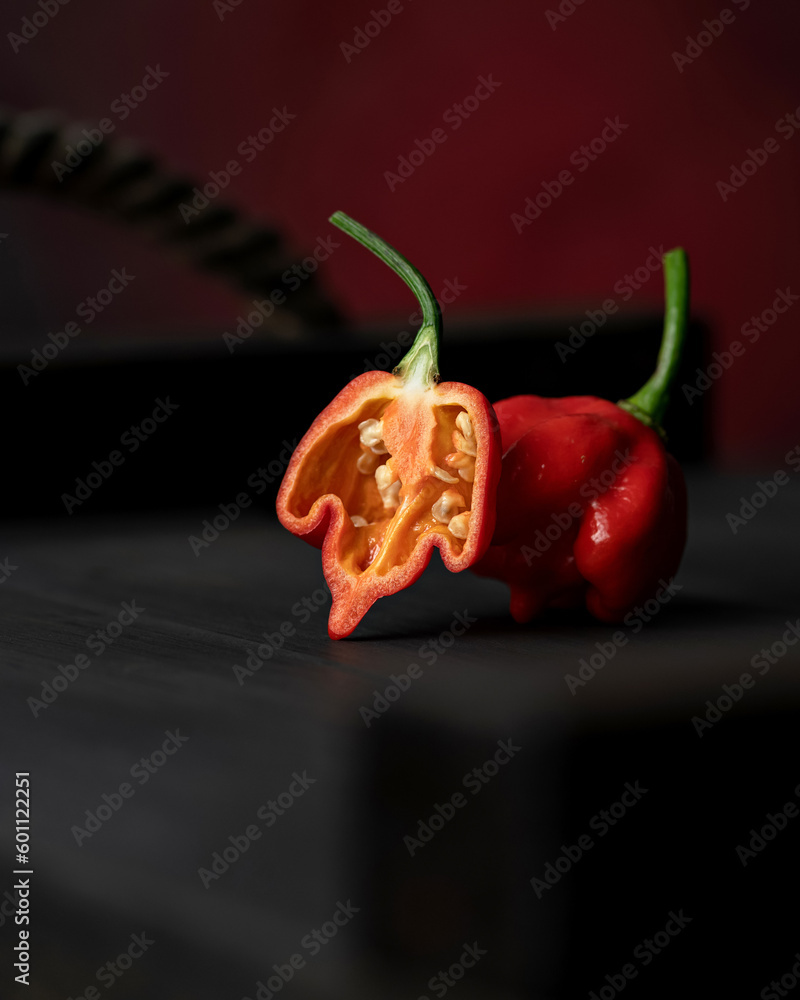 Hot pepper Scorpion Red. Whole pepper and half stand on wooden surface ...
