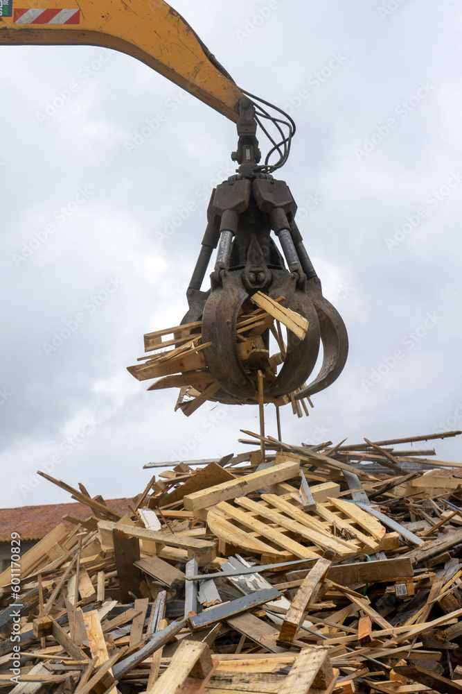 Claw machine stacking wooden pallets for recycling in a waste treatment ...