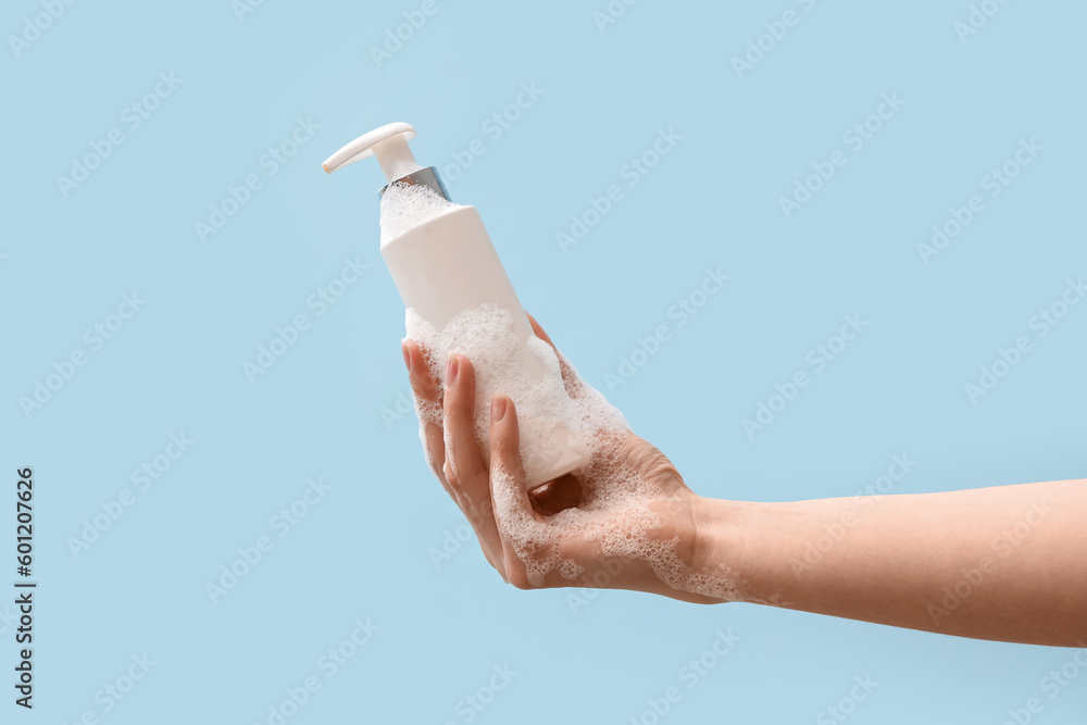 Hand holding bottle of shampoo on light blue background Stock Photo ...