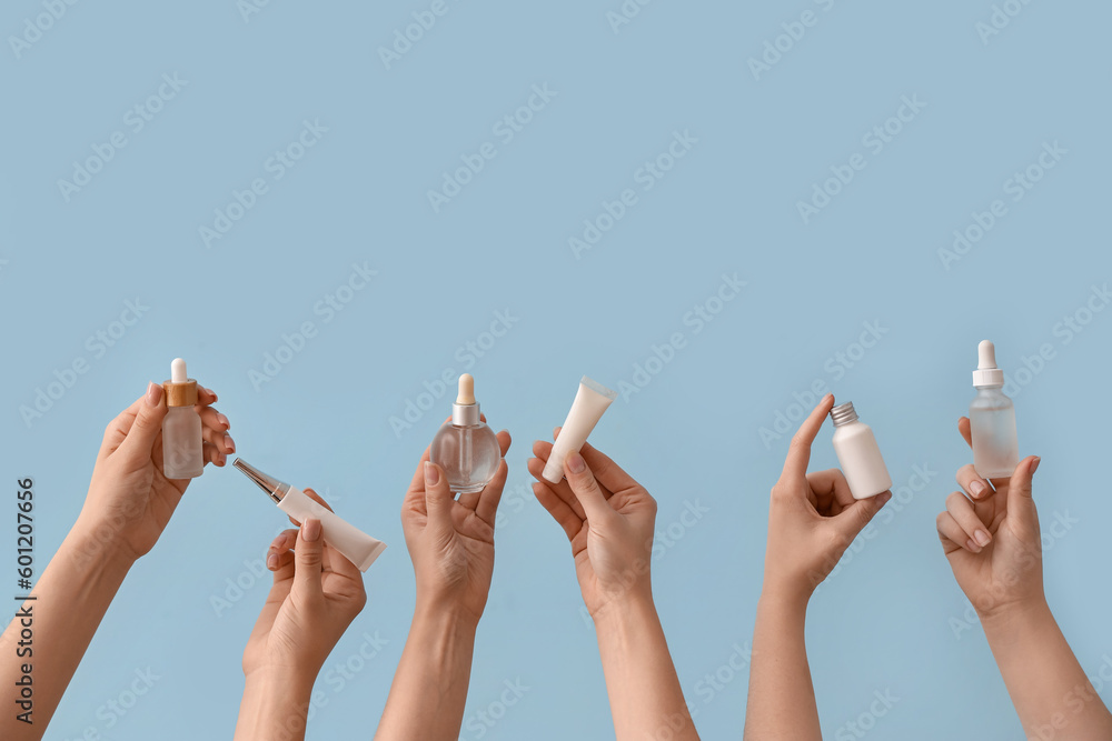 Hands holding different cosmetic products on light blue background ...