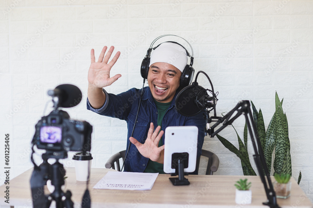 Young Asian male vlogger in headphones recording video at creative home ...