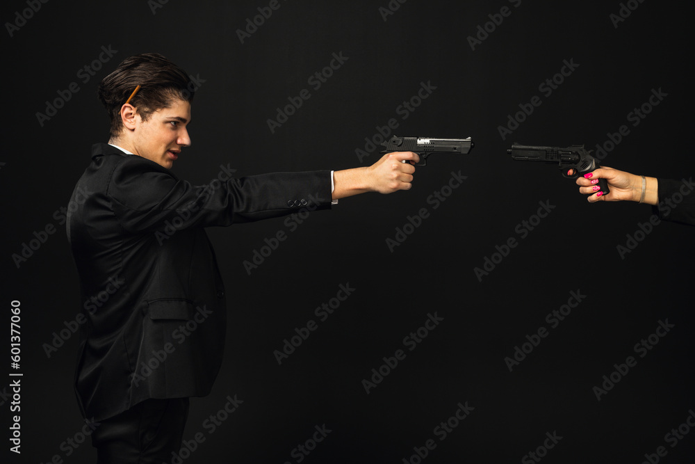 Young mafia member with a slicked back hair, in black suit, smokes a ...