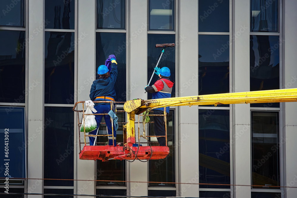 Stockfoto Workers washing window of an office building in crane bucket ...
