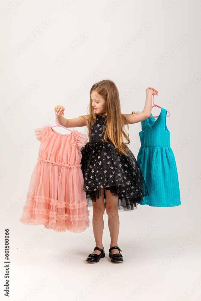 Little girl choosing dresses on white background. Child in black dress ...