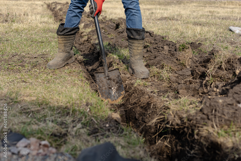 Drainage ditch. A man is digging a ditch. Laying a drainage pipe ...