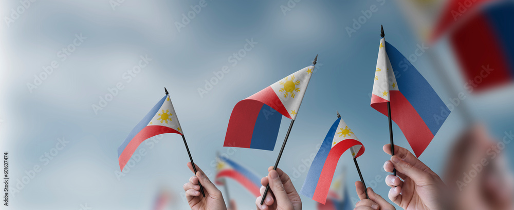 Poster A group of people holding small flags of the Philippines in ...