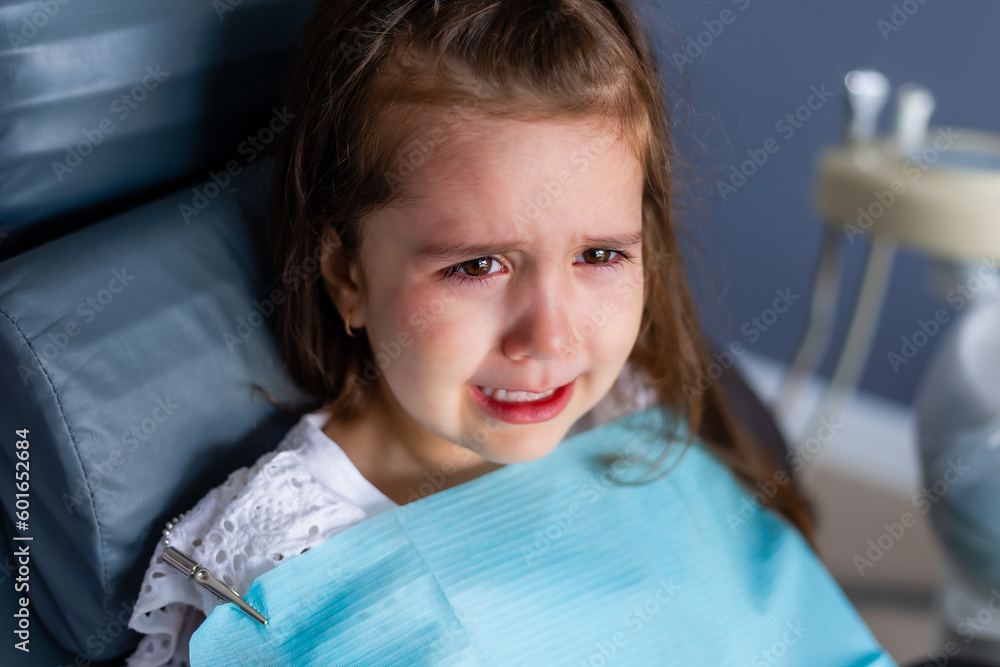 little brunette girl at the reception is crying, afraid. Pediatric ...