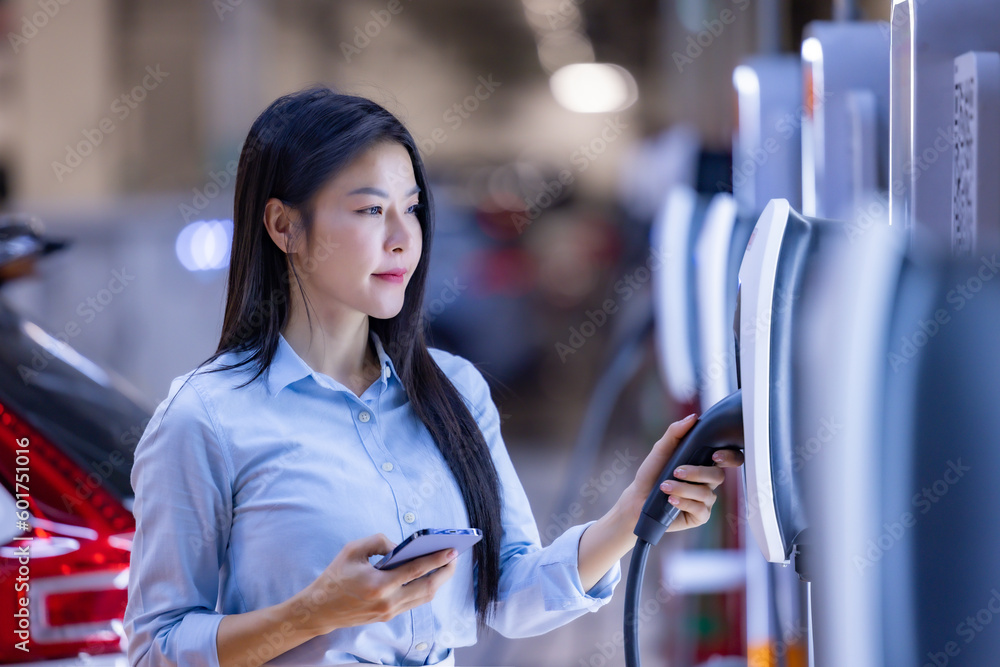 Young Asian woman holding the CCS 2 EV charging connector at EV ...