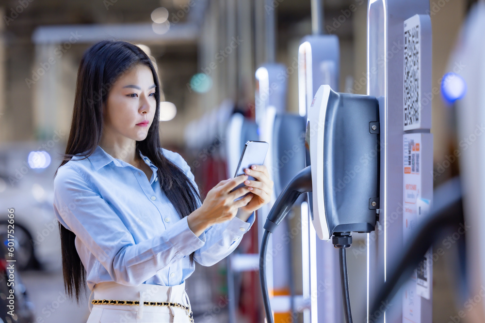 Woman holding the CCS 2 EV charging connector at EV charging station in ...