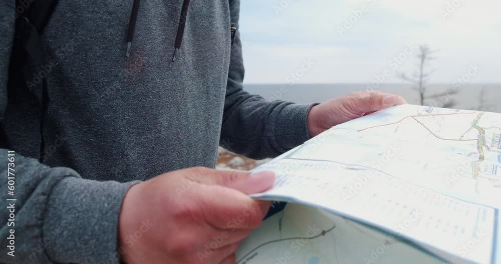 Traveler Looks at a Paper Map Against the Backdrop of Rocks Ocean Close ...