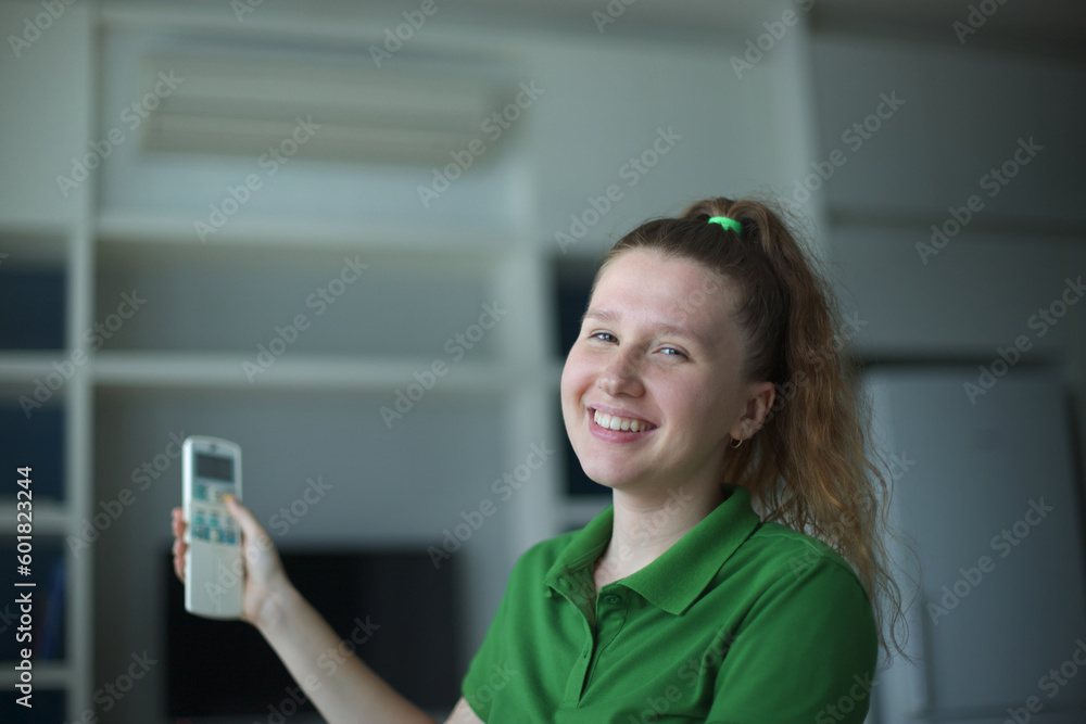 Young happy woman with air conditioner remote control using air ...