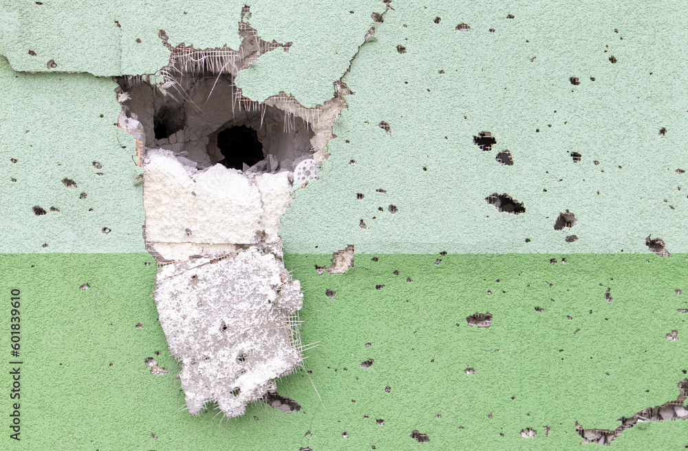 Holes from bullets and shrapnel in the wall on the front line. Scars of ...