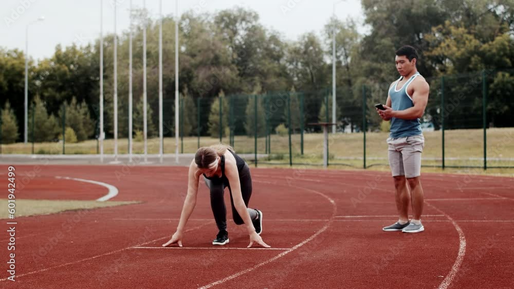 Young female athlete starts running from a low-start position while her ...