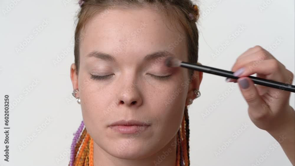 Makeup artists hand uses makeup brush to apply shadows on eyelids of ...