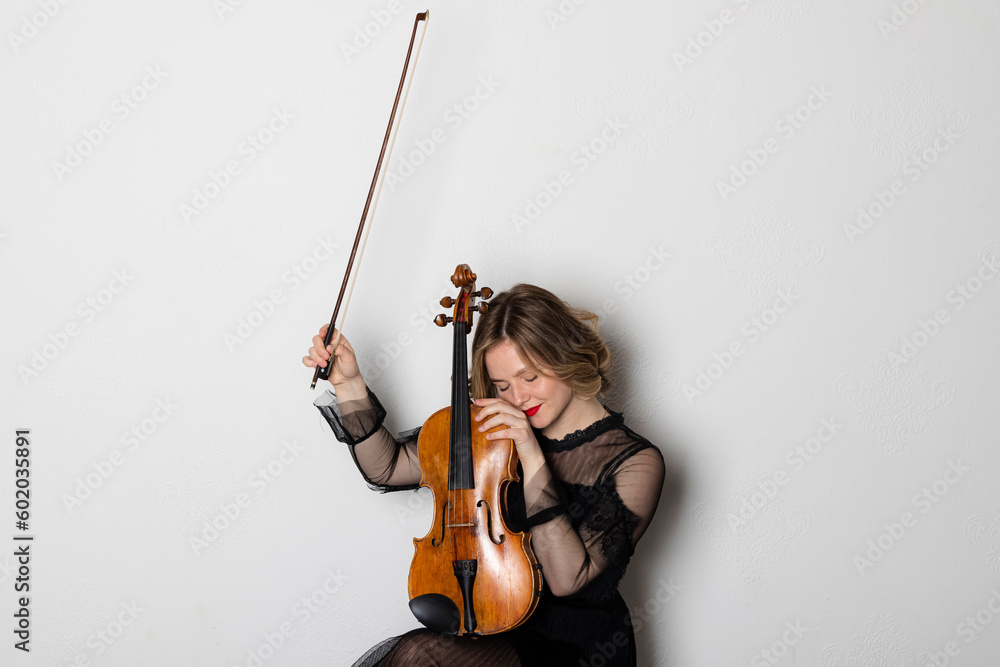 Young elegant blonde girl playing a violin. Portrait of a female ...