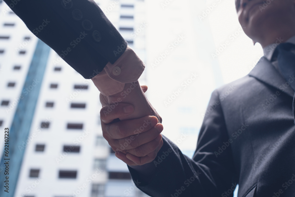 Foto de Businessmen making handshake with buildings in the city as ...