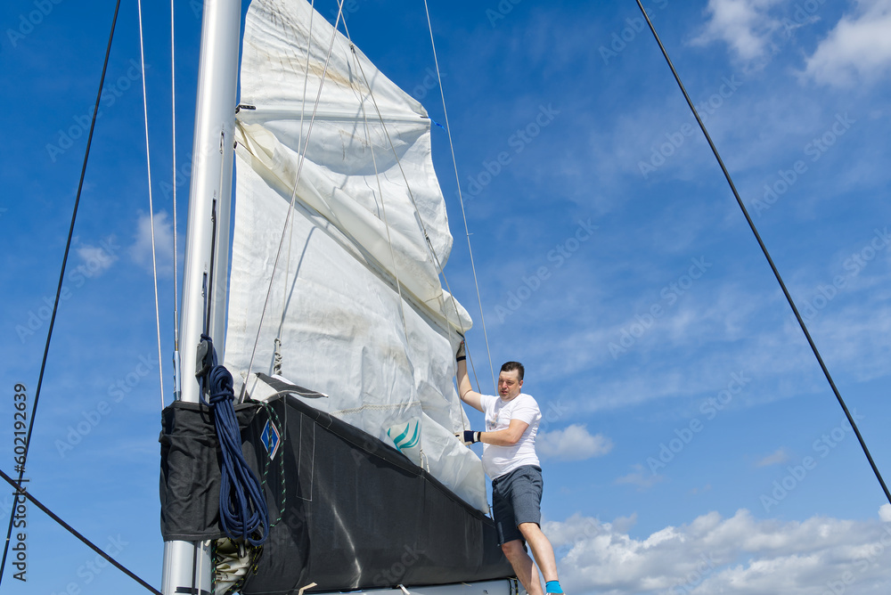 Raising the sail on a yacht. Young man captan lifting the sail of ...
