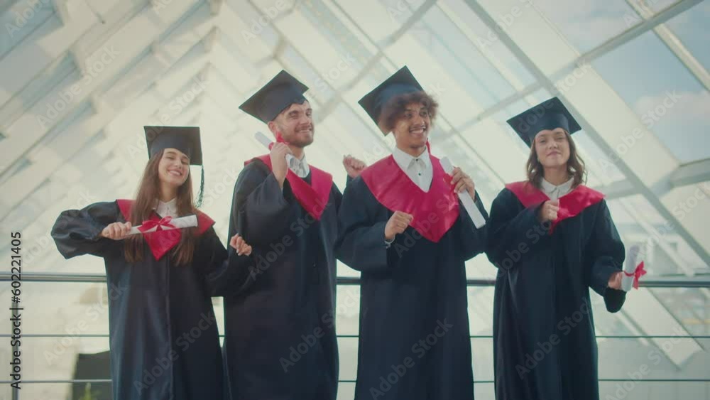 Positive Group of Successful Graduates Dancing With Diplomas in Hallway ...