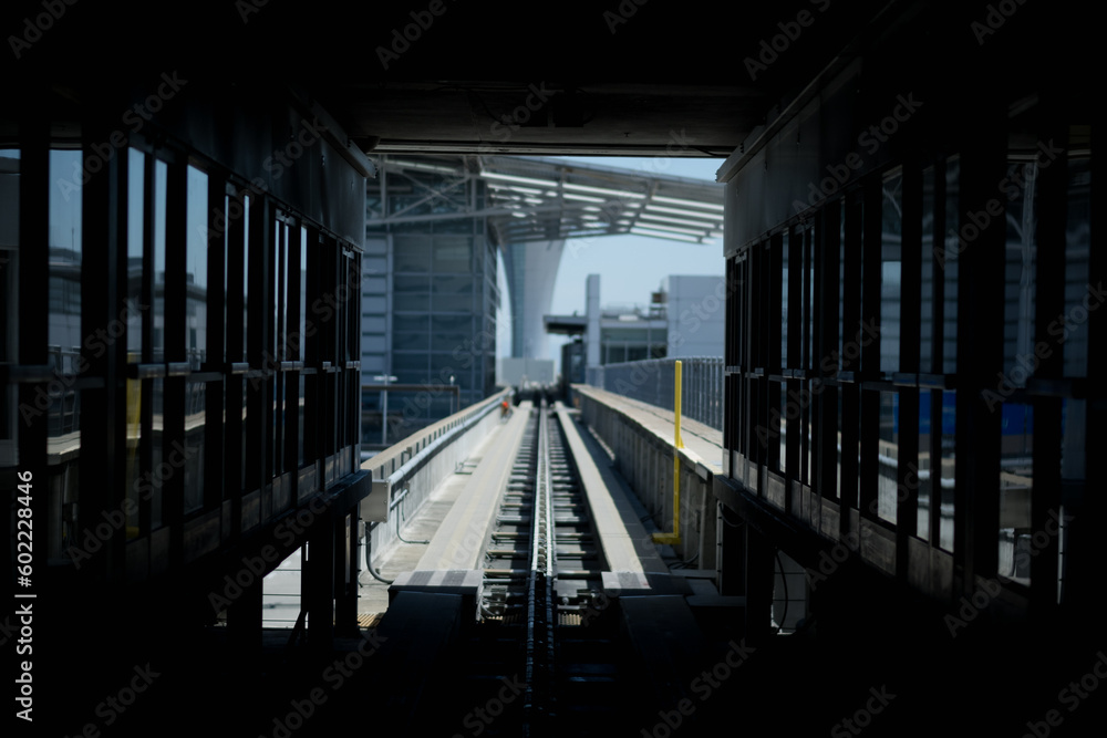 An enclosed train station surrounds a railway. In the distance, the ...
