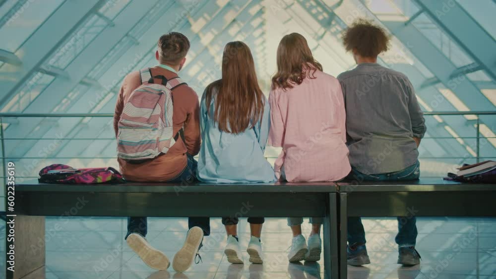 Back view of Students Sitting on Bench in the University HallWay During ...