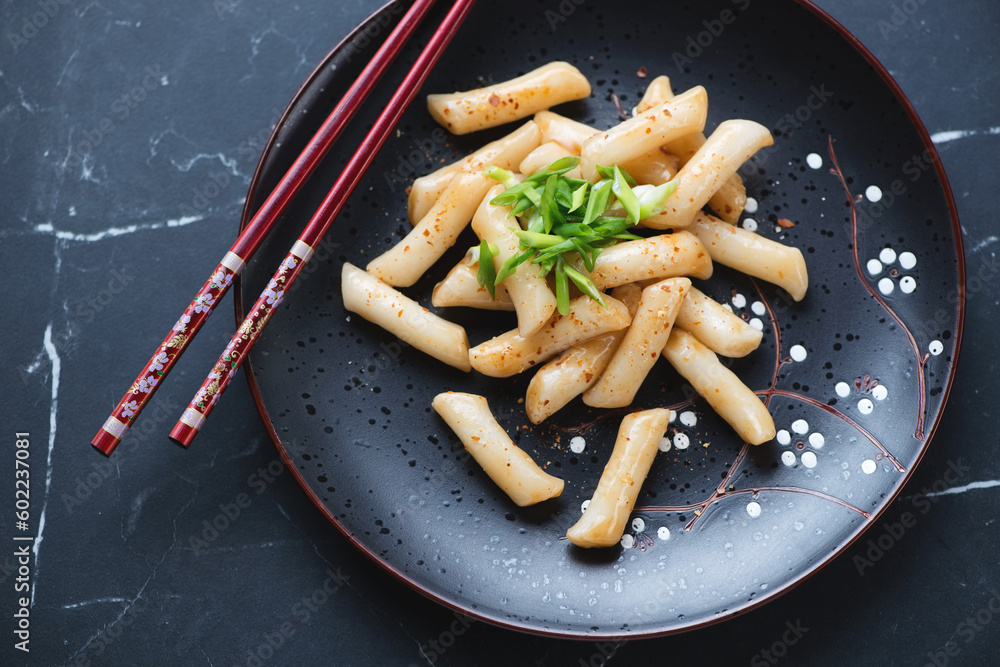 Black plate with korean tteokbokki or traditional rice cakes ...