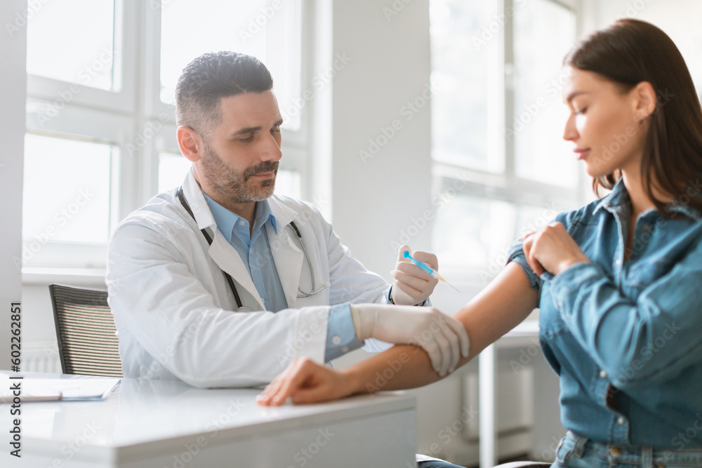 Protecting your health. Young woman getting vaccine shot against ...