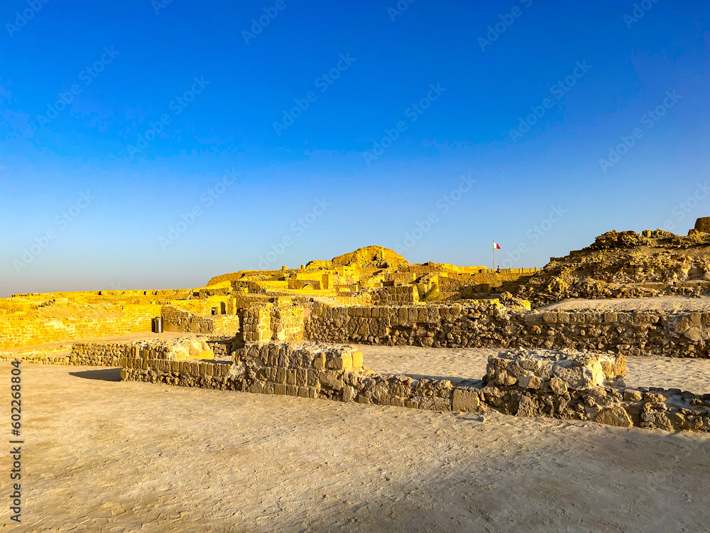 Ancient village in Qalat al-Bahrain with fort and flag at the ...