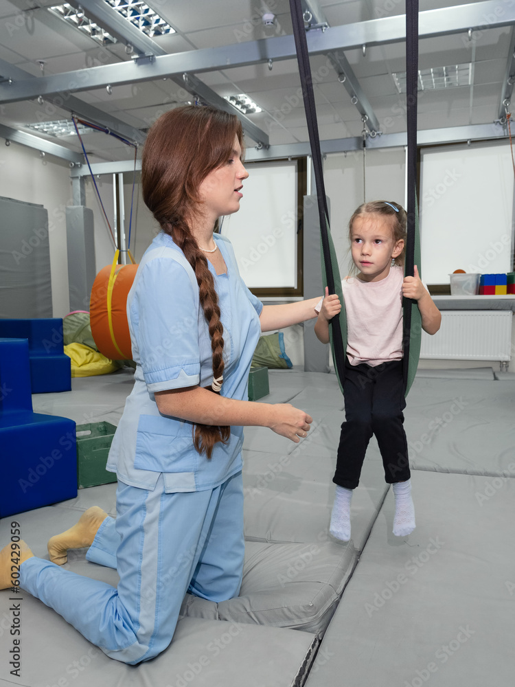 Child with physiotherapist on swing during sensory integration session ...