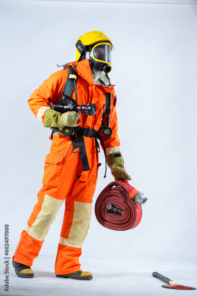 Standing tall and ready a firefighter wearing a yellow helmet grips the ...