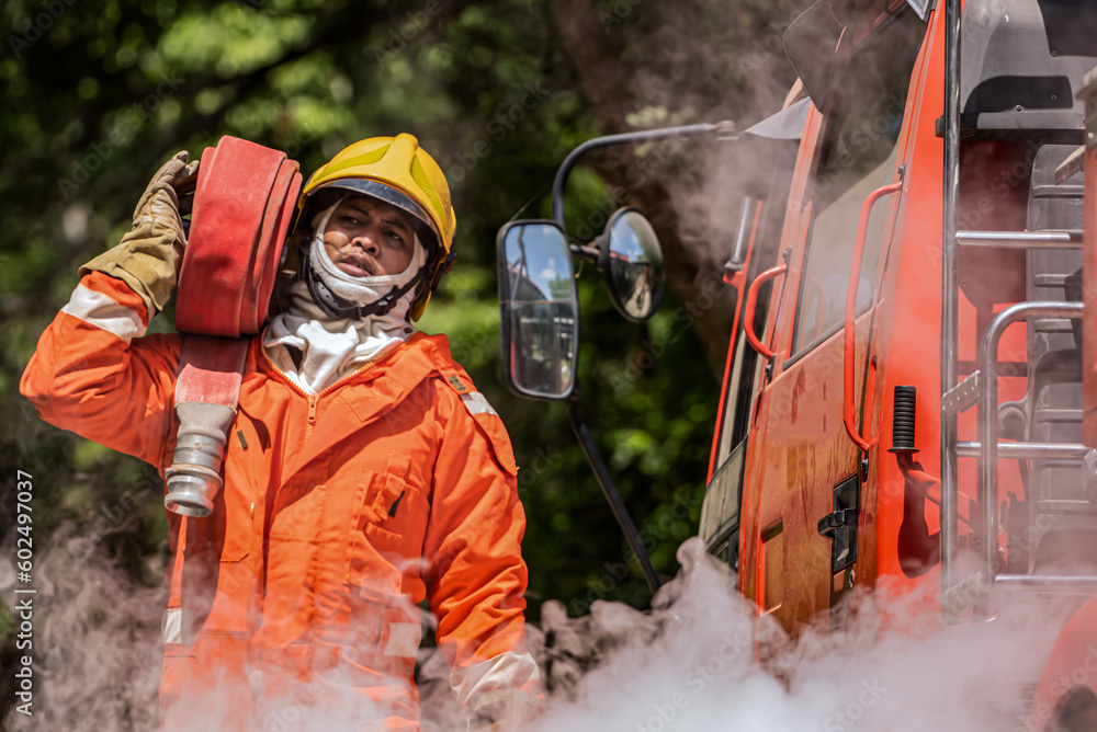 Amidst billowing clouds of smoke, a firefighter stands tall shouldering ...