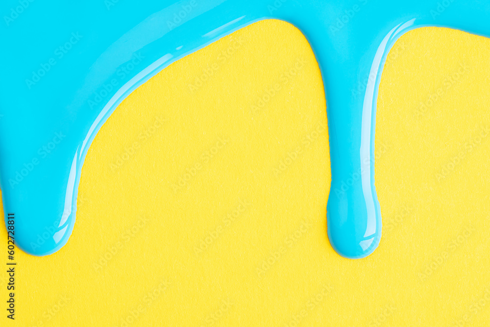 Light blue liquid drops of paint color flow down on yellow paper ...