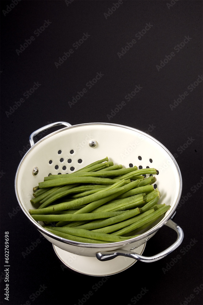 Kitchen collander filled with green beans brightly lit on isolated ...