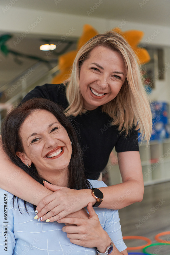 Two women share a heartfelt embrace while at a preschool, showcasing ...