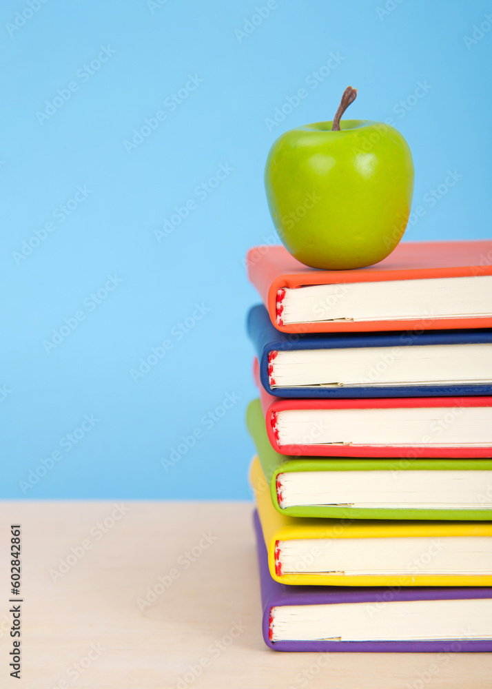 Bright colorful bound books stacked on a light wood table with blue ...