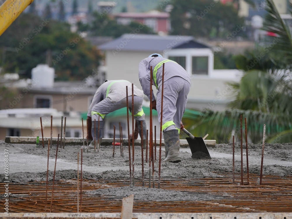 Construction site workers levelling and smoothing fresh cement on cast ...
