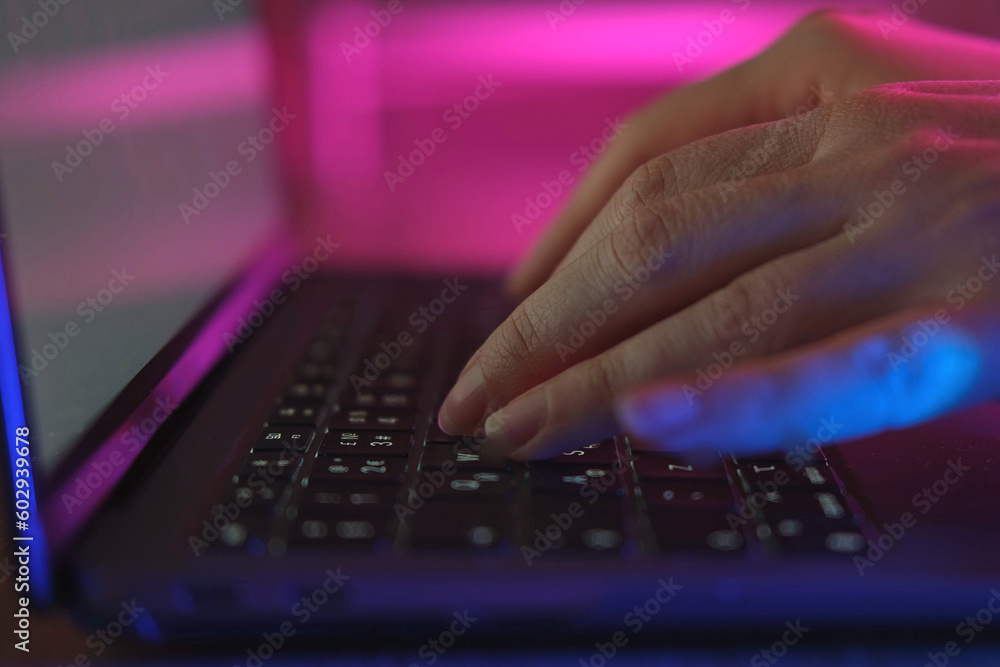 Person typing at laptop computer at night. Female uses keyboard, shakes ...