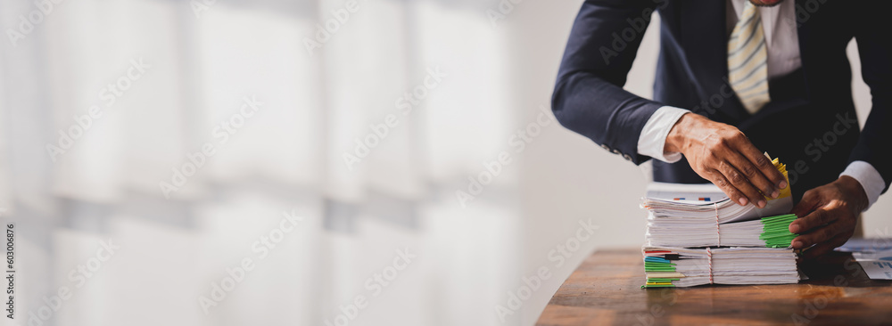 work from office A businessman works a bunch of paper files to find ...