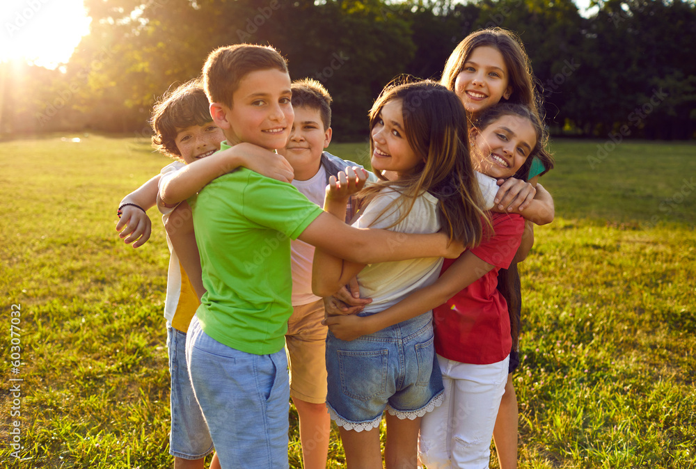Group of friendly cheerful children standing in circle and hugging each ...
