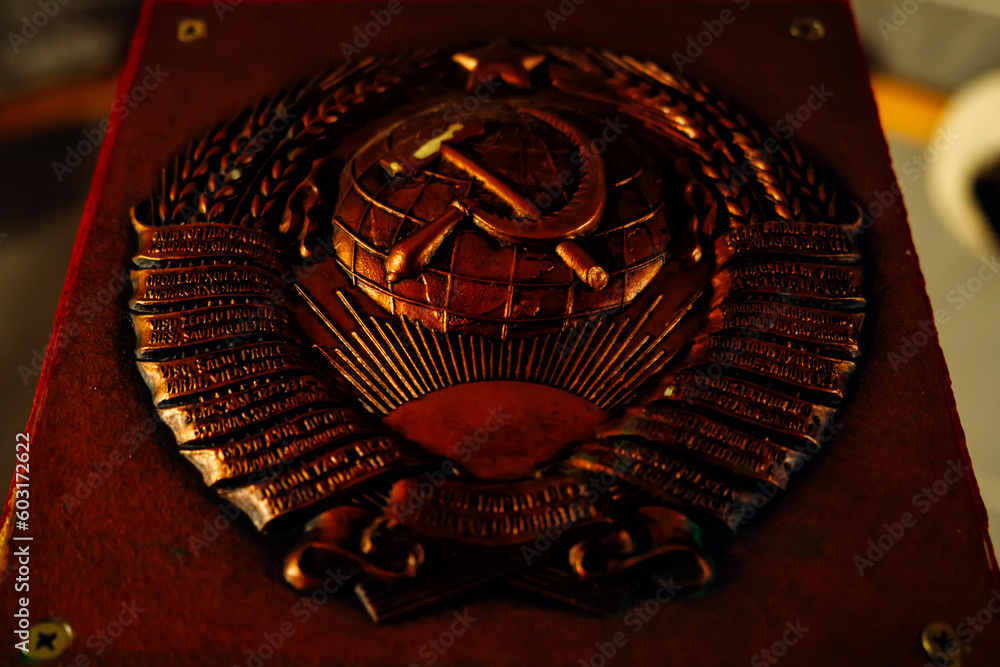 Old Soviet coat of arms made of red copper, close-up. Symbol of former ...