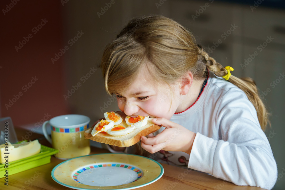 Little smiling girl have a breakfast at home. Preschool child eating ...