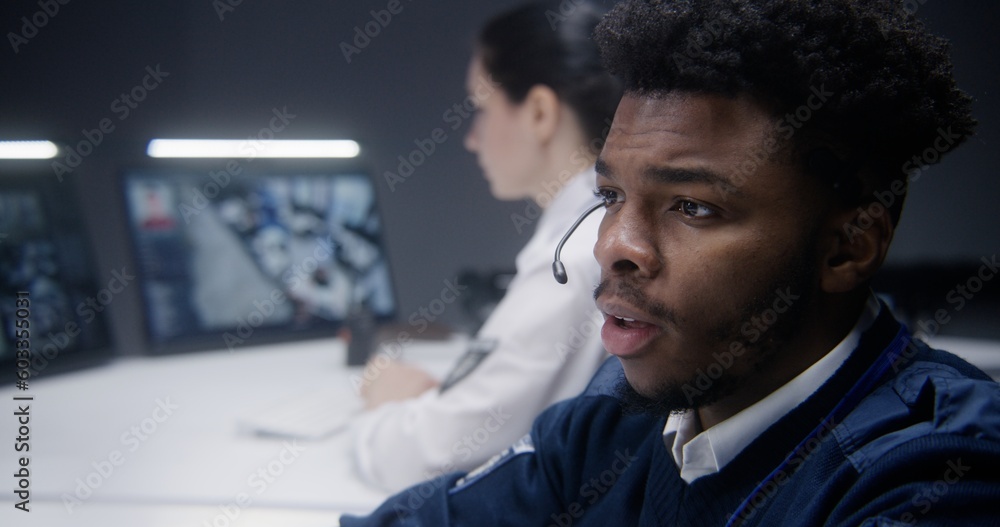 African American security operator in headset talks with colleague and ...