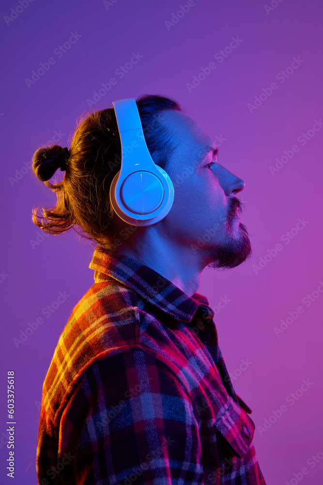 Side view portrait of young man listening to music in headphones with ...