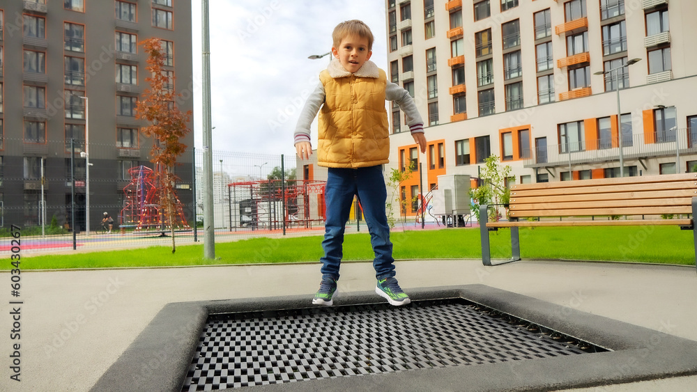 Active laughing boy jumping up high on the trampoline and having fun ...