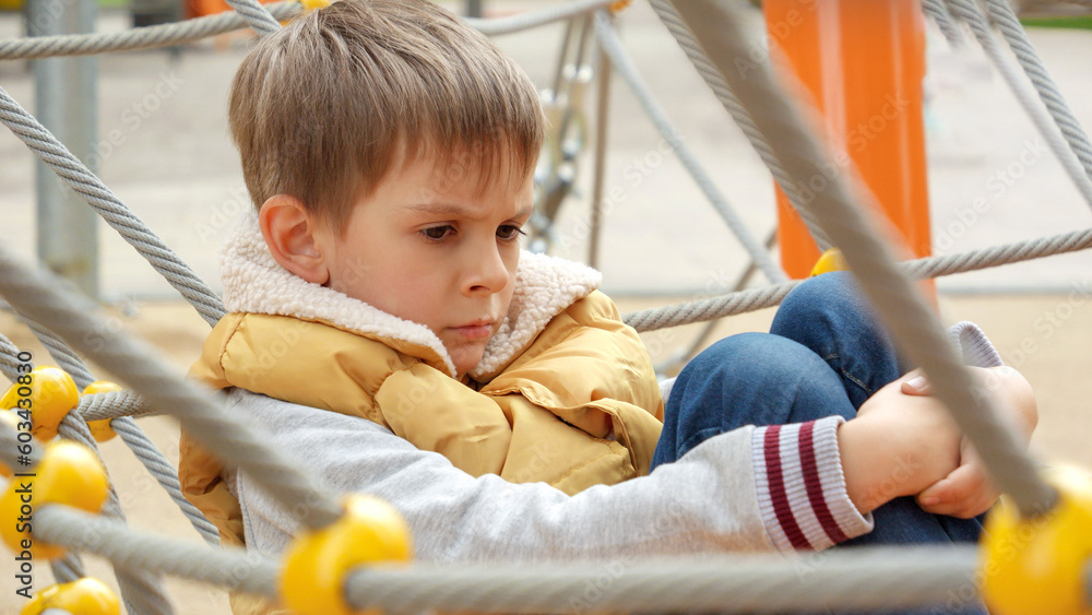 Upset and sad little boy being victim of bullying sitting alone on ...