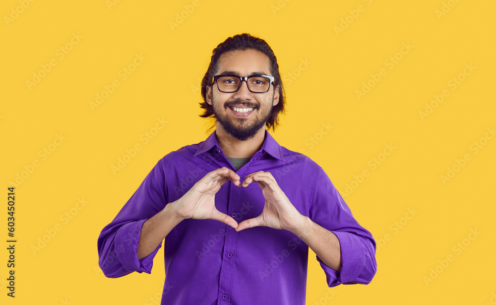 Portrait of smiling Indian man in glasses isolated on yellow studio ...